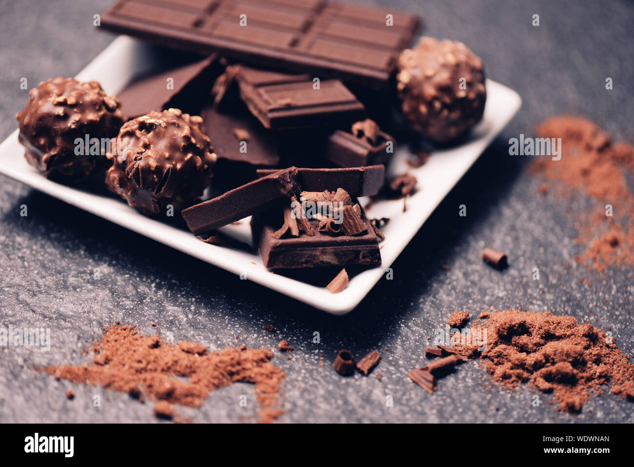 chocolate bar and chocolate ball on white plate on the dark background ...