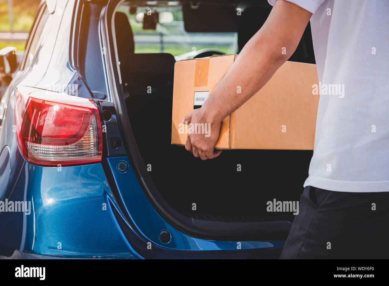 Delivery man is delivering cardboard box to customers via private car ...
