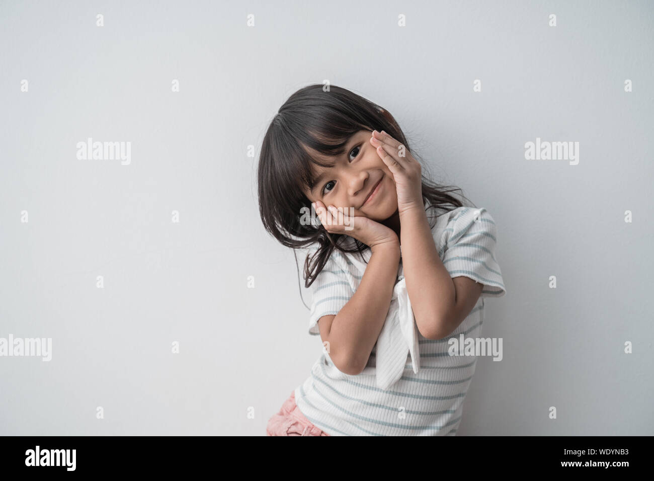 cute smiling little girl with hands on cheek in the isolated background ...