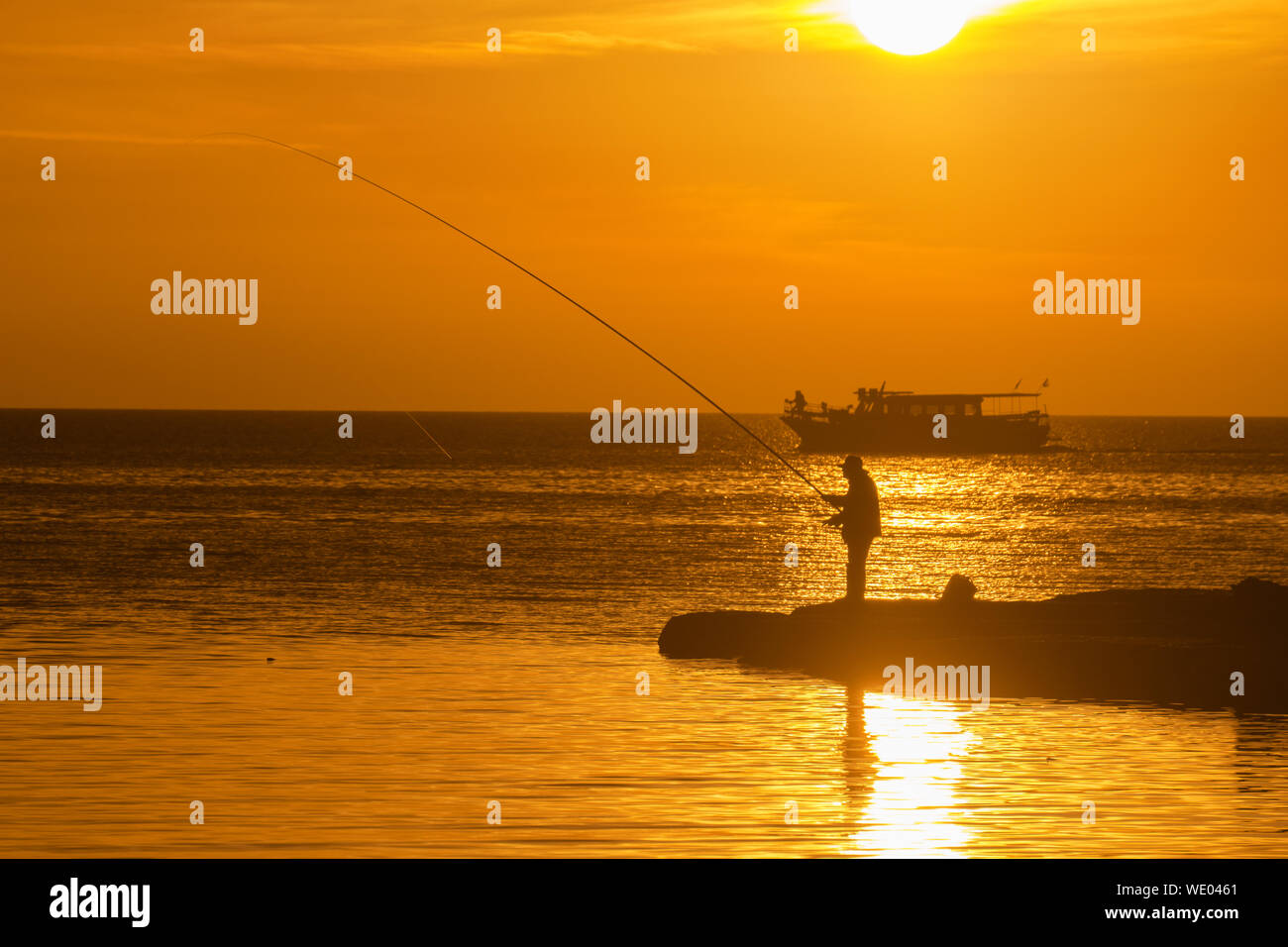 A man fishing in front of the sun in Byblos harbour in Byblos Lebanon ...