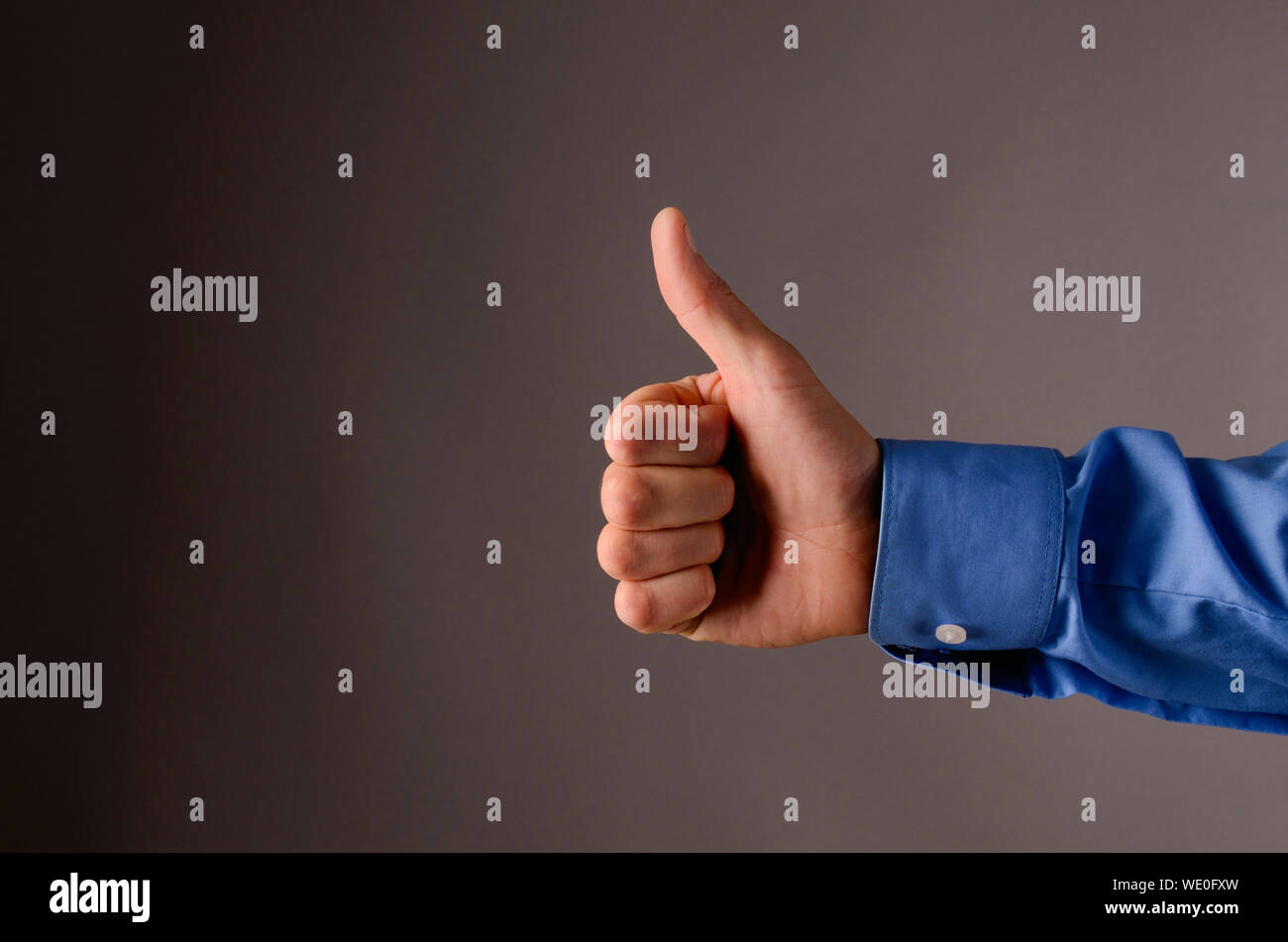 Close-up Of Human Hand With Thumbs Up Sign Against Gray Background ...