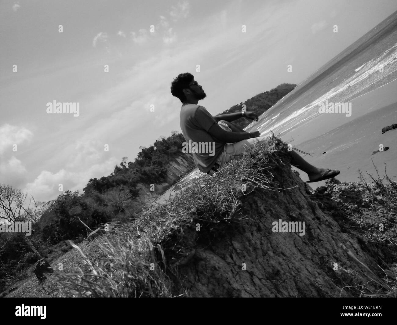 Young Man Sitting On Cliff At Beach Stock Photo - Alamy