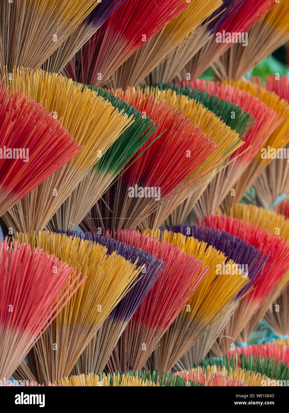 Bundles of yellow, pink, green and purple incense sticks displayed in ...