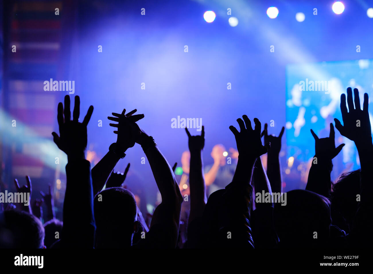Fans cheering musicians on stage at live rock music concert, back view ...