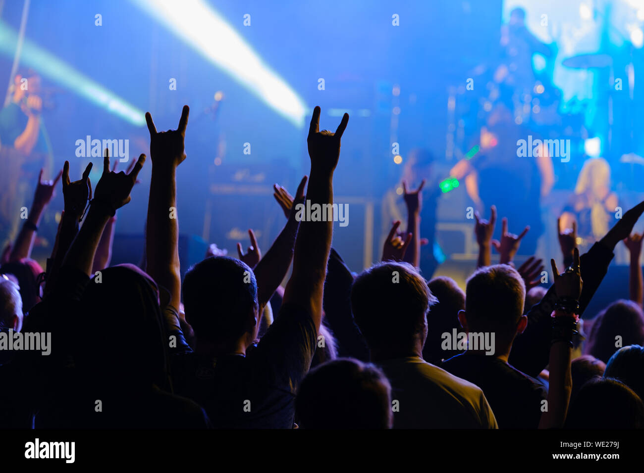 Fans cheering musicians on stage at live rock music concert, back view ...