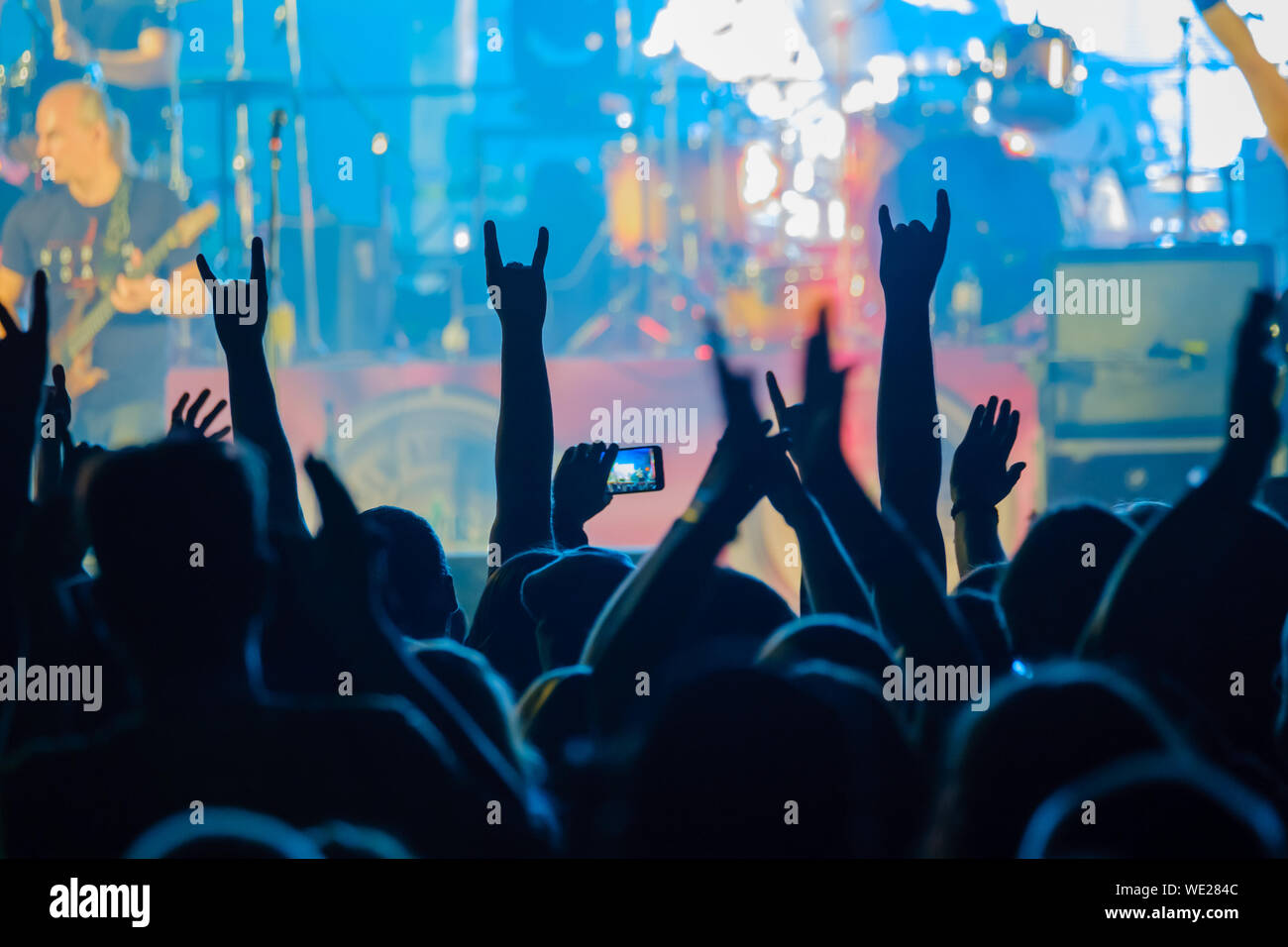 Fans cheering musicians on stage at live rock music concert, back view ...