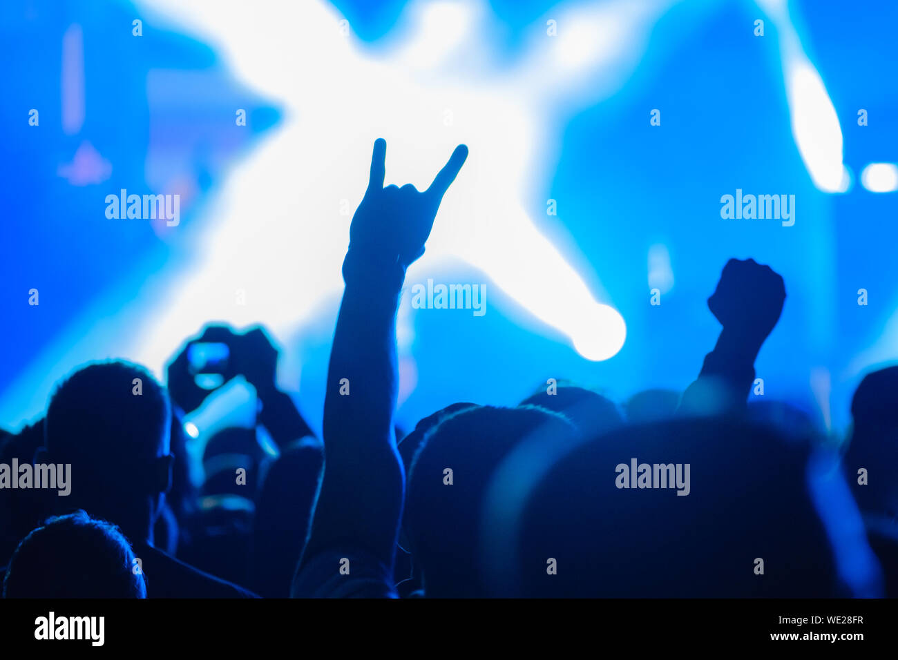 Fans cheering musicians on stage at live rock music concert, back view ...