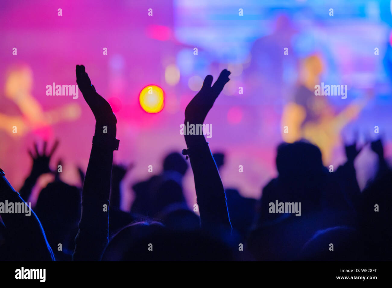 Fans cheering musicians on stage at live rock music concert, back view ...