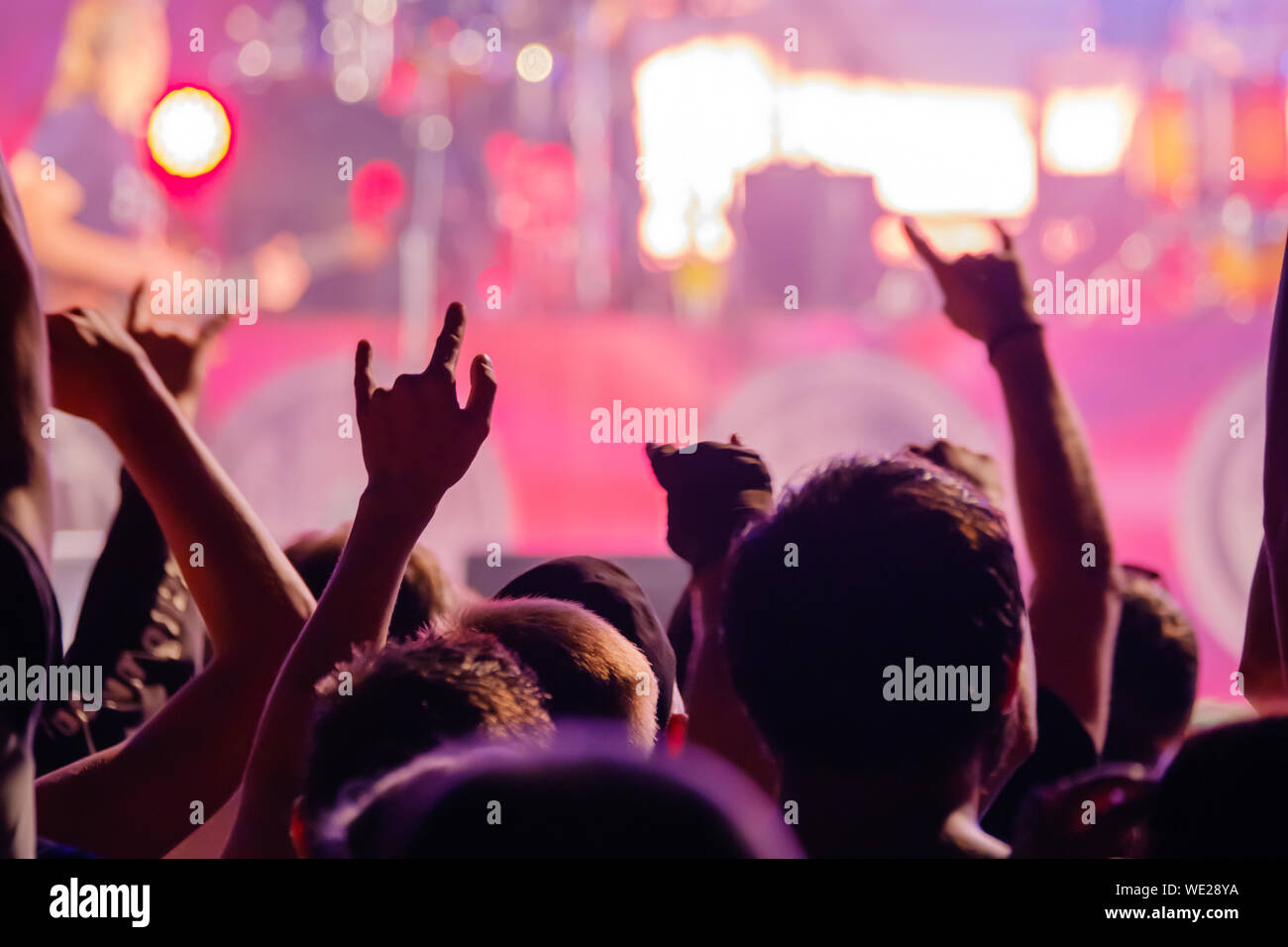 Fans cheering musicians on stage at live rock music concert, back view ...