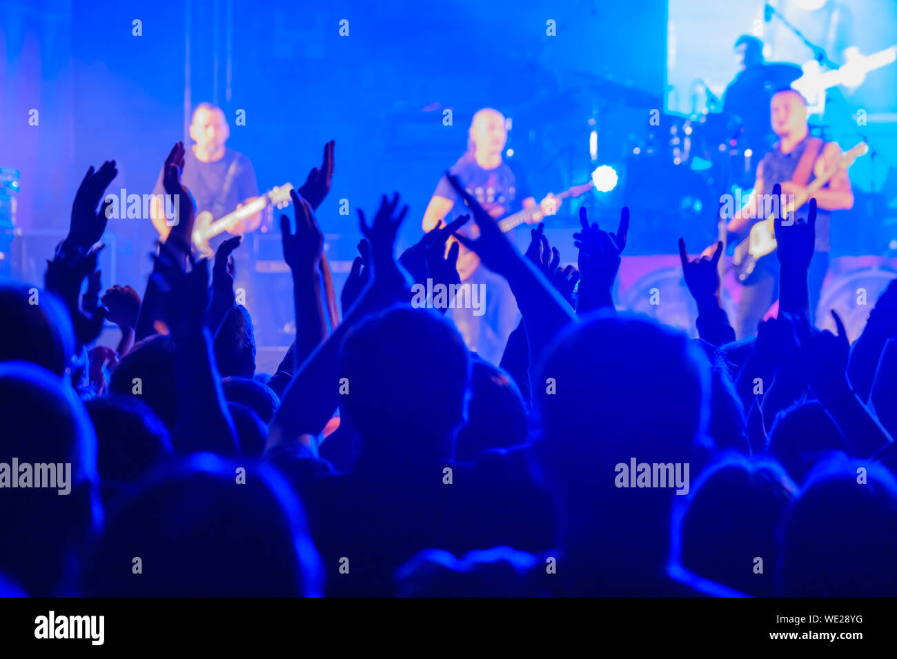 Fans cheering musicians on stage at live rock music concert, back view ...