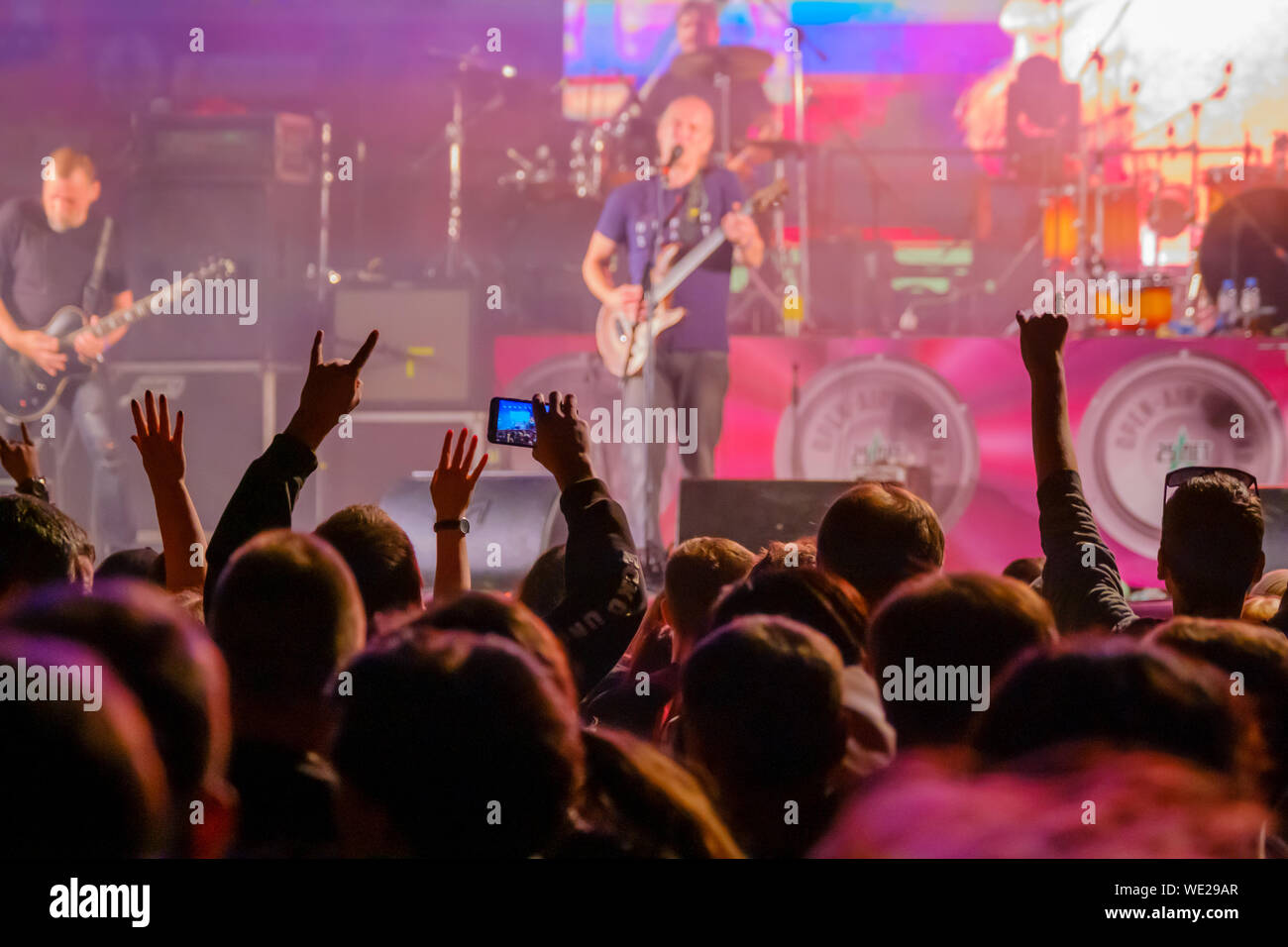 Fans cheering musicians on stage at live rock music concert, back view ...