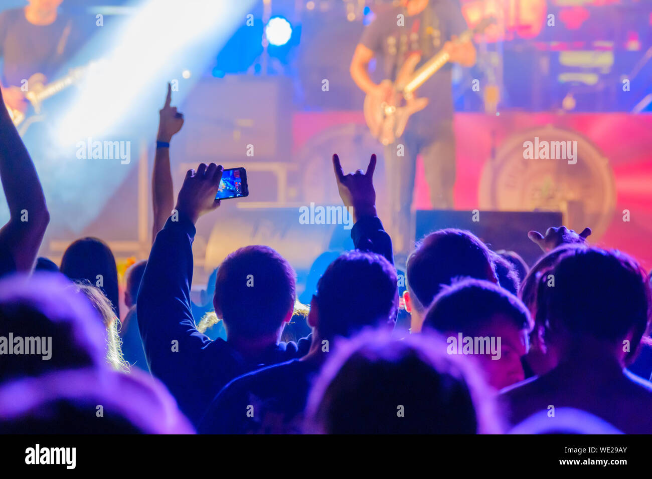 Fans cheering musicians on stage at live rock music concert, back view ...