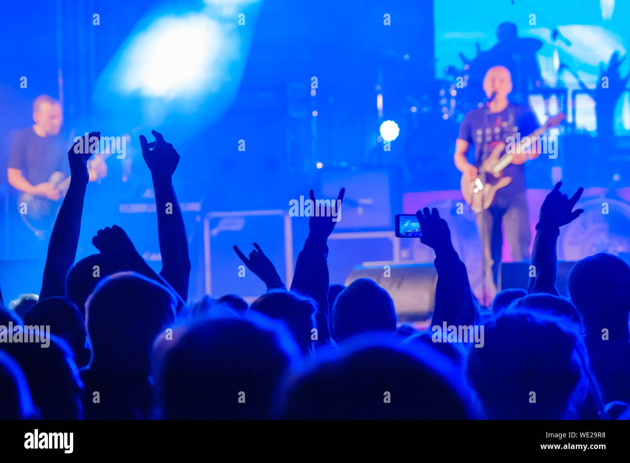 Fans cheering musicians on stage at live rock music concert, back view ...