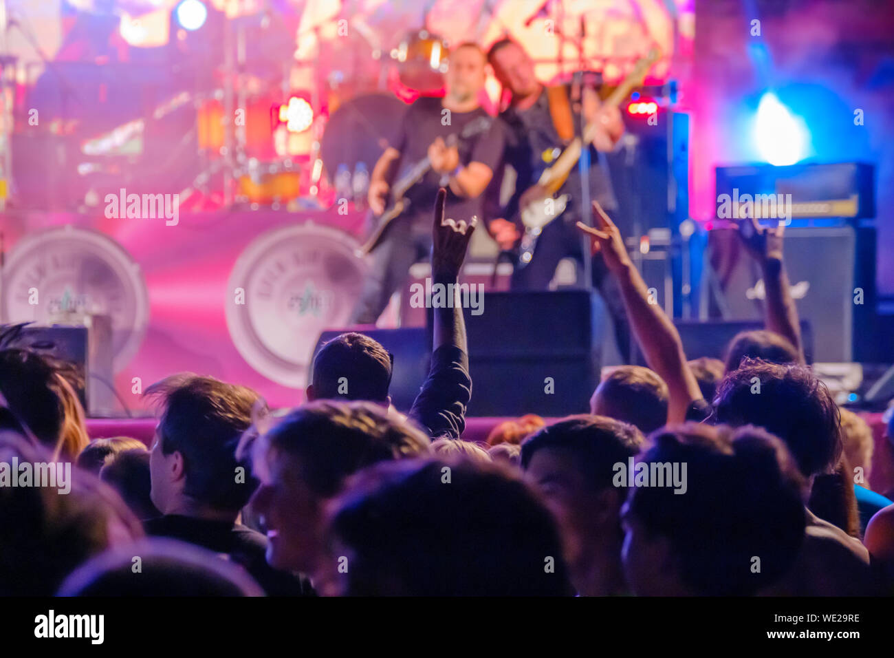 Fans cheering musicians on stage at live rock music concert, back view ...
