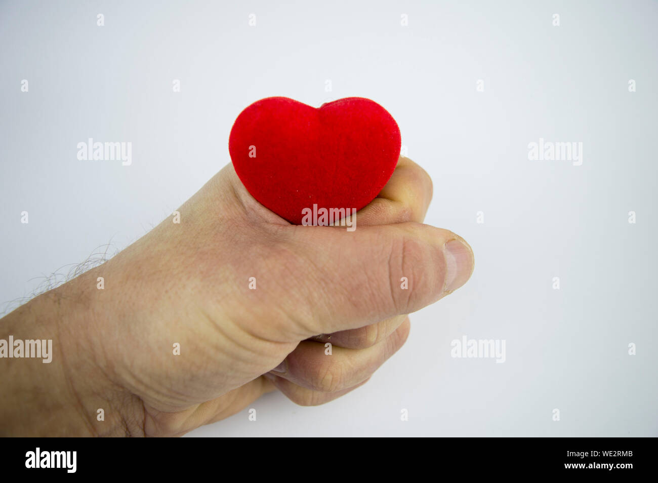 Heart in a man's fist on a white background, there is free space to ...
