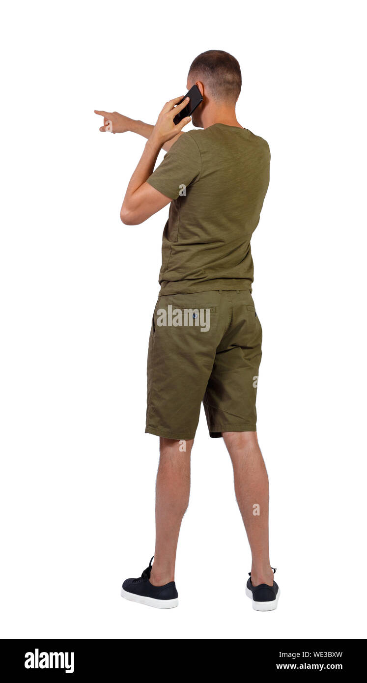 Back view of pointing man in shorts who is looking into the smartphone ...