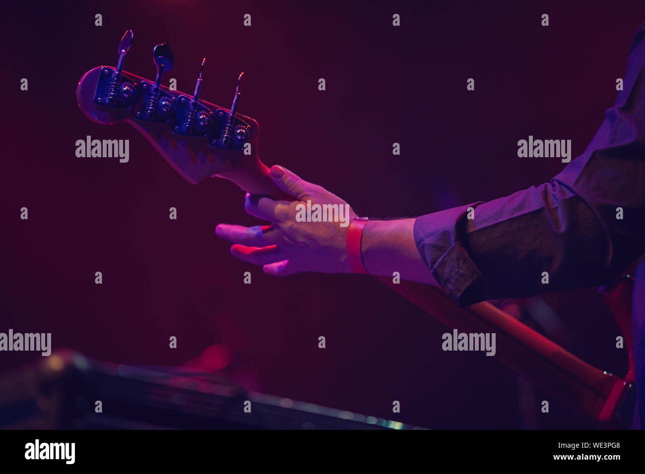 Bass guitarist playing solo part on rock concert stage in music hall ...