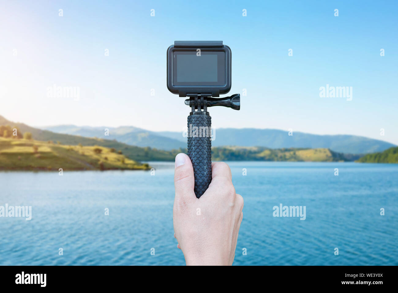 Hand hold stick and action camera and recording lake. Blank screen for ...