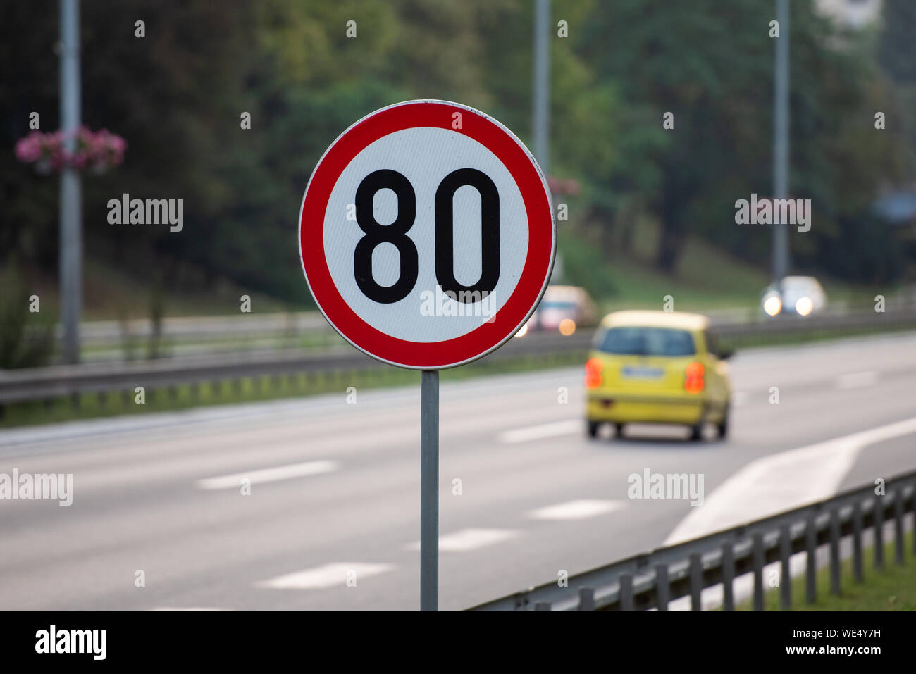 80km/h Speed limit sign a highway with small yellow car in the ...