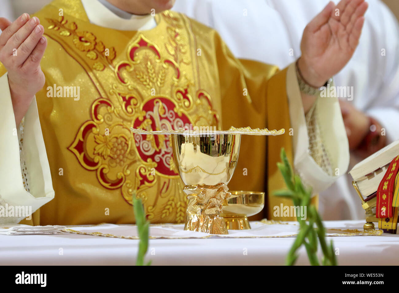 Chalice on the altar and priest celebrating mass in the background ...