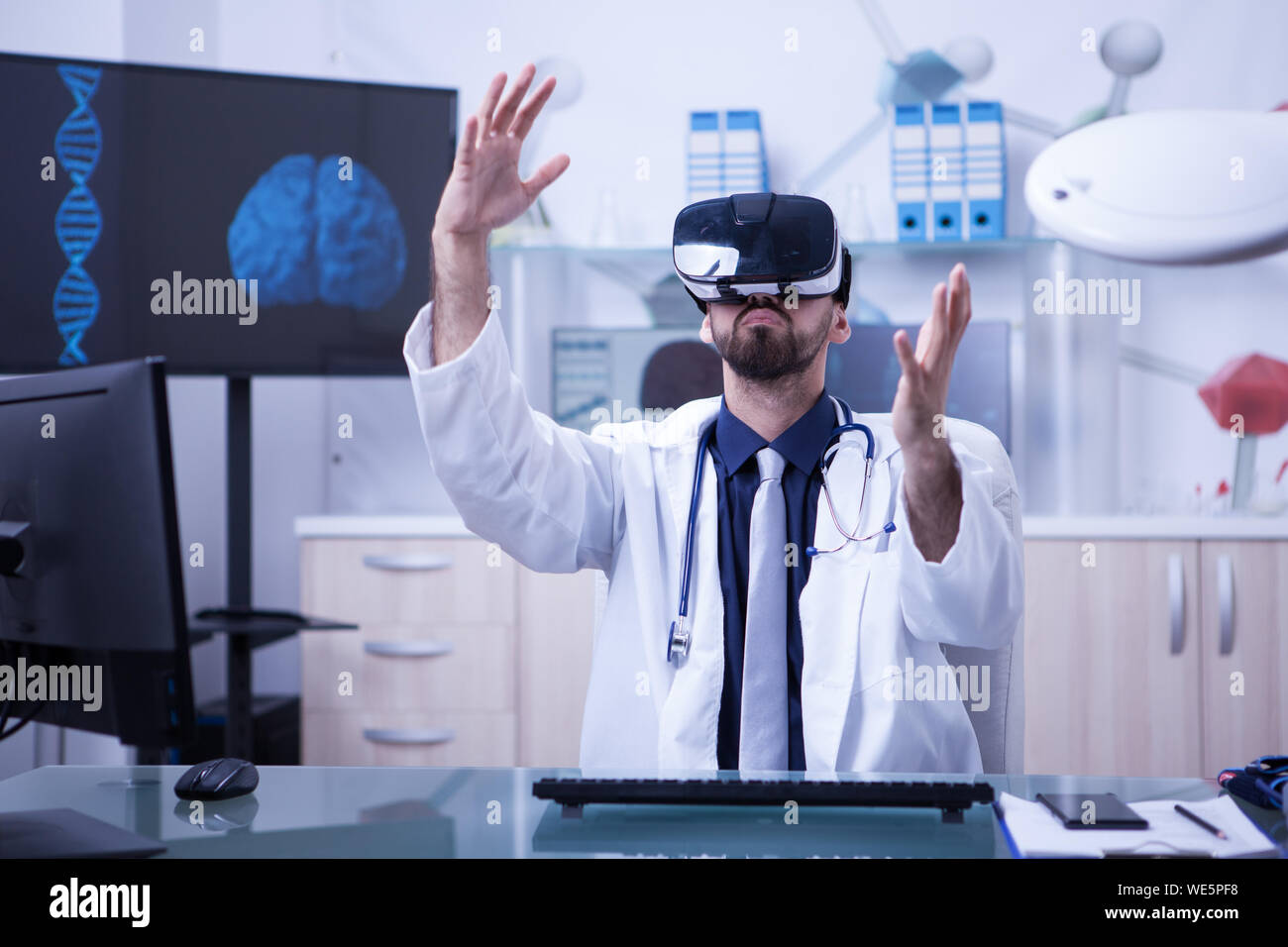 Smart doctor wearing virtual reality goggles in modern clinic office ...