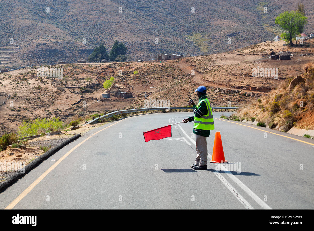 Road worker holds in hand red flag prohibiting traffic, travel ...