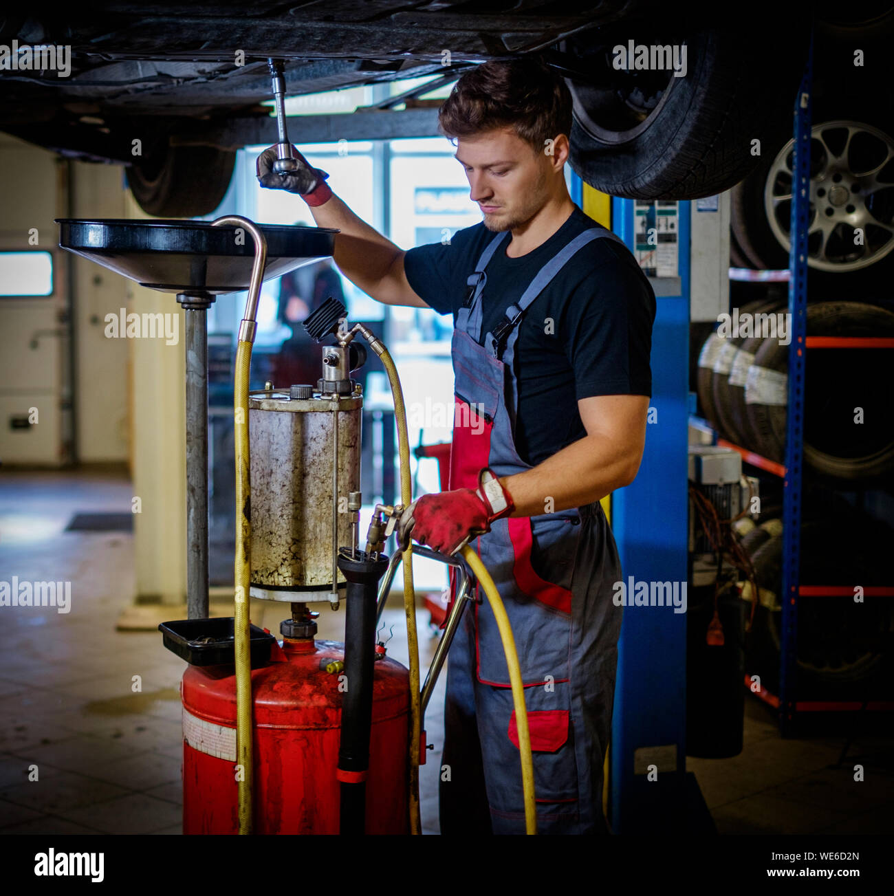 Car mechanic changes oil in a workshop Stock Photo - Alamy