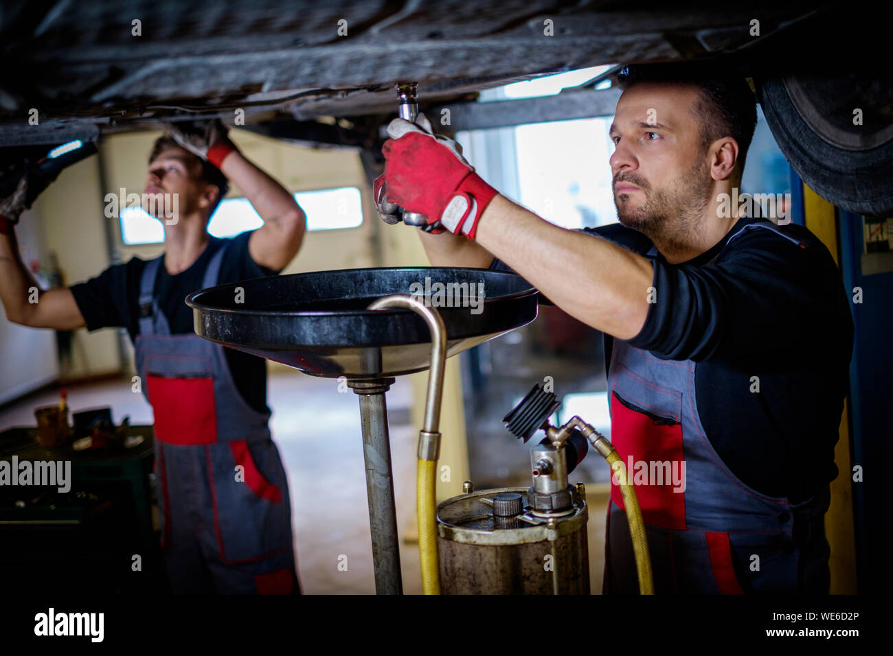 Car mechanic changes oil in a workshop Stock Photo - Alamy