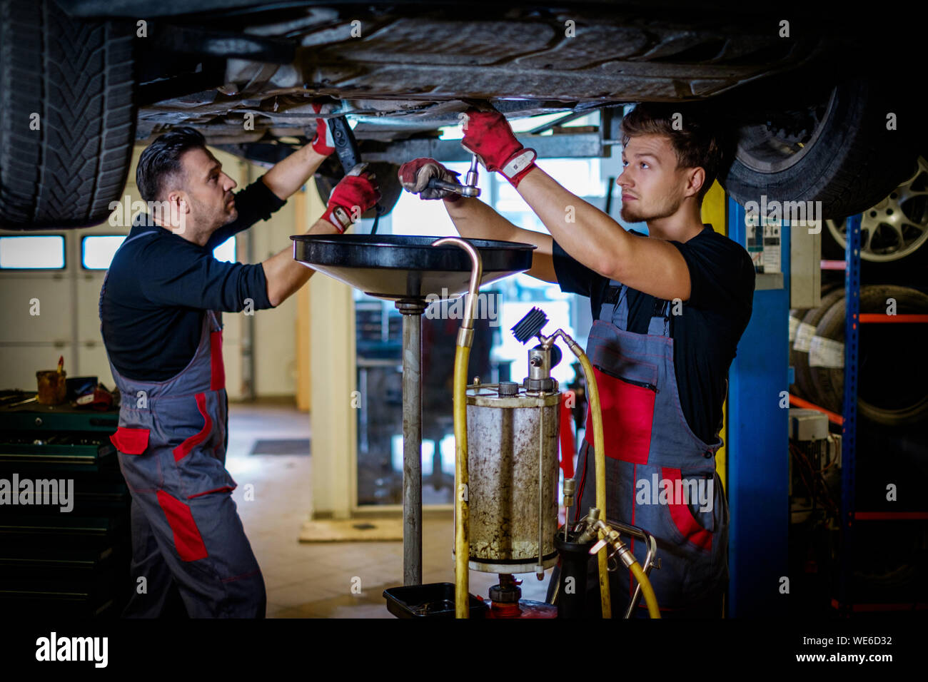 Car mechanic changes oil in a workshop Stock Photo - Alamy
