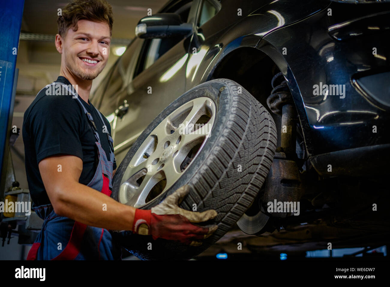 Car mechanic replacing wheel in a workshop Stock Photo - Alamy