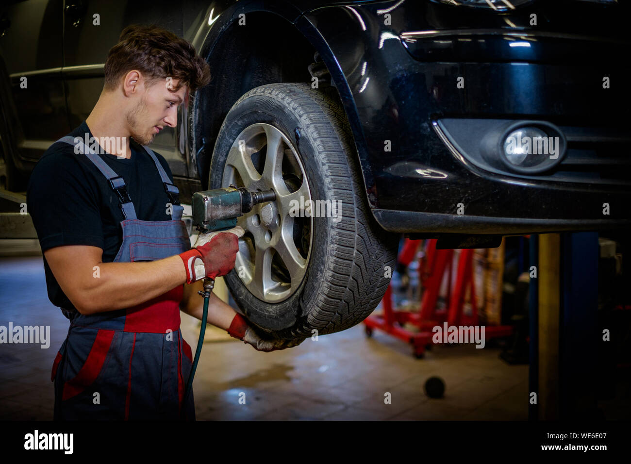 Car mechanic replacing wheel in a workshop Stock Photo - Alamy