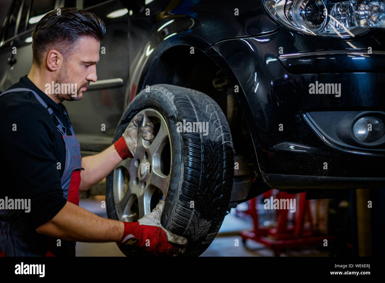 Car mechanic replacing wheel in a workshop Stock Photo - Alamy