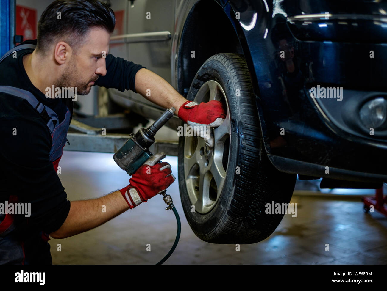 Car mechanic replacing wheel in a workshop Stock Photo - Alamy