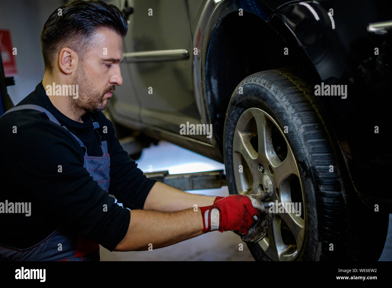 Car mechanic replacing wheel in a workshop Stock Photo - Alamy