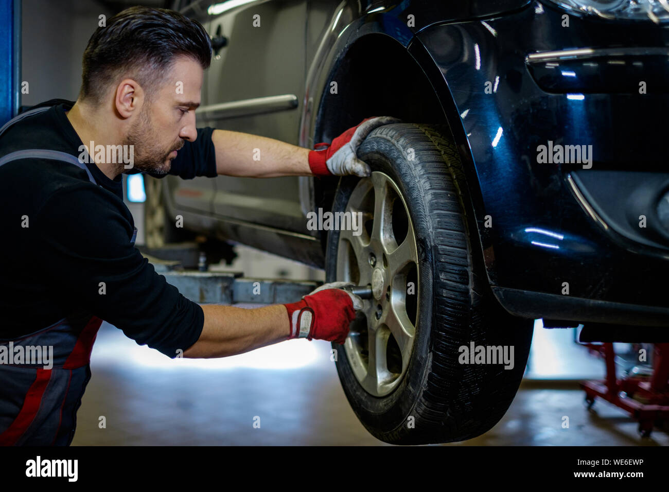 Car mechanic replacing wheel in a workshop Stock Photo - Alamy