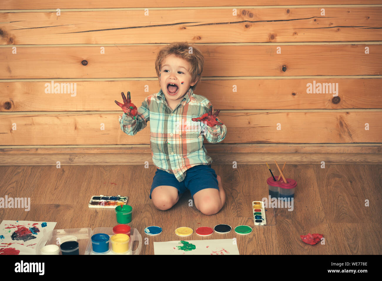 Child happy shouting with colored hands, gouache paints and drawings ...