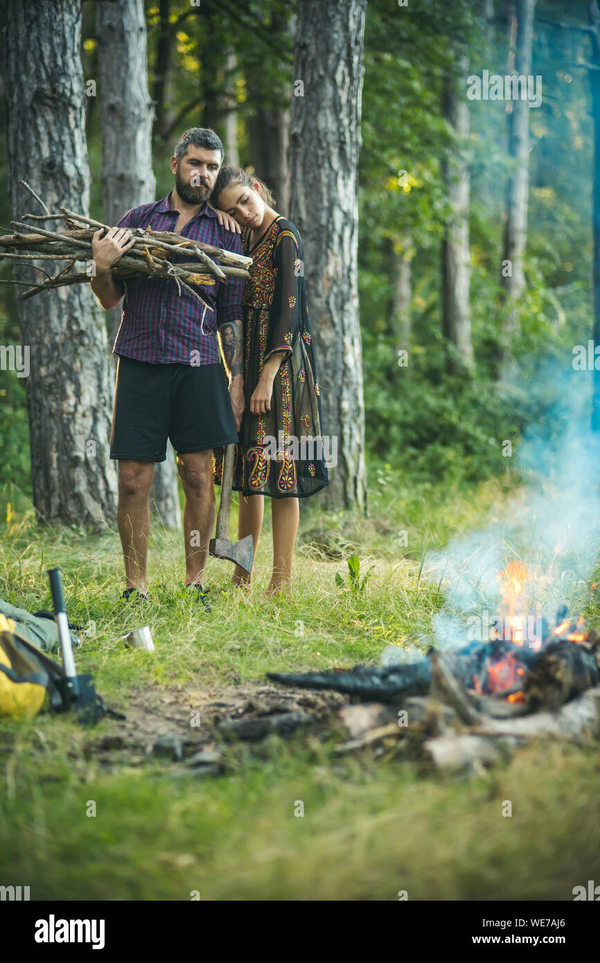 Woman hug man lumberjack with axe and bunch of firewood. Couple in love ...
