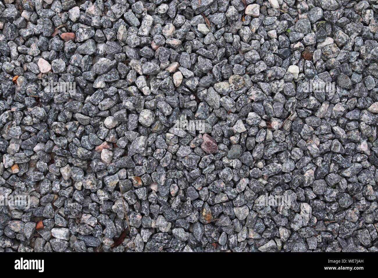 Detailed close up view on pebbles and stones on a gravel ground texture ...