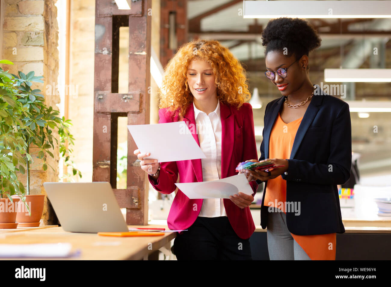 Two interior designers standing near window sill and discussing new ...