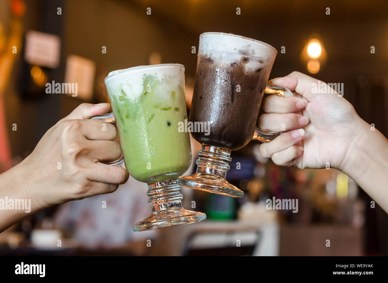 Friends toasting, saying cheers holding glass of iced chocolate and ...