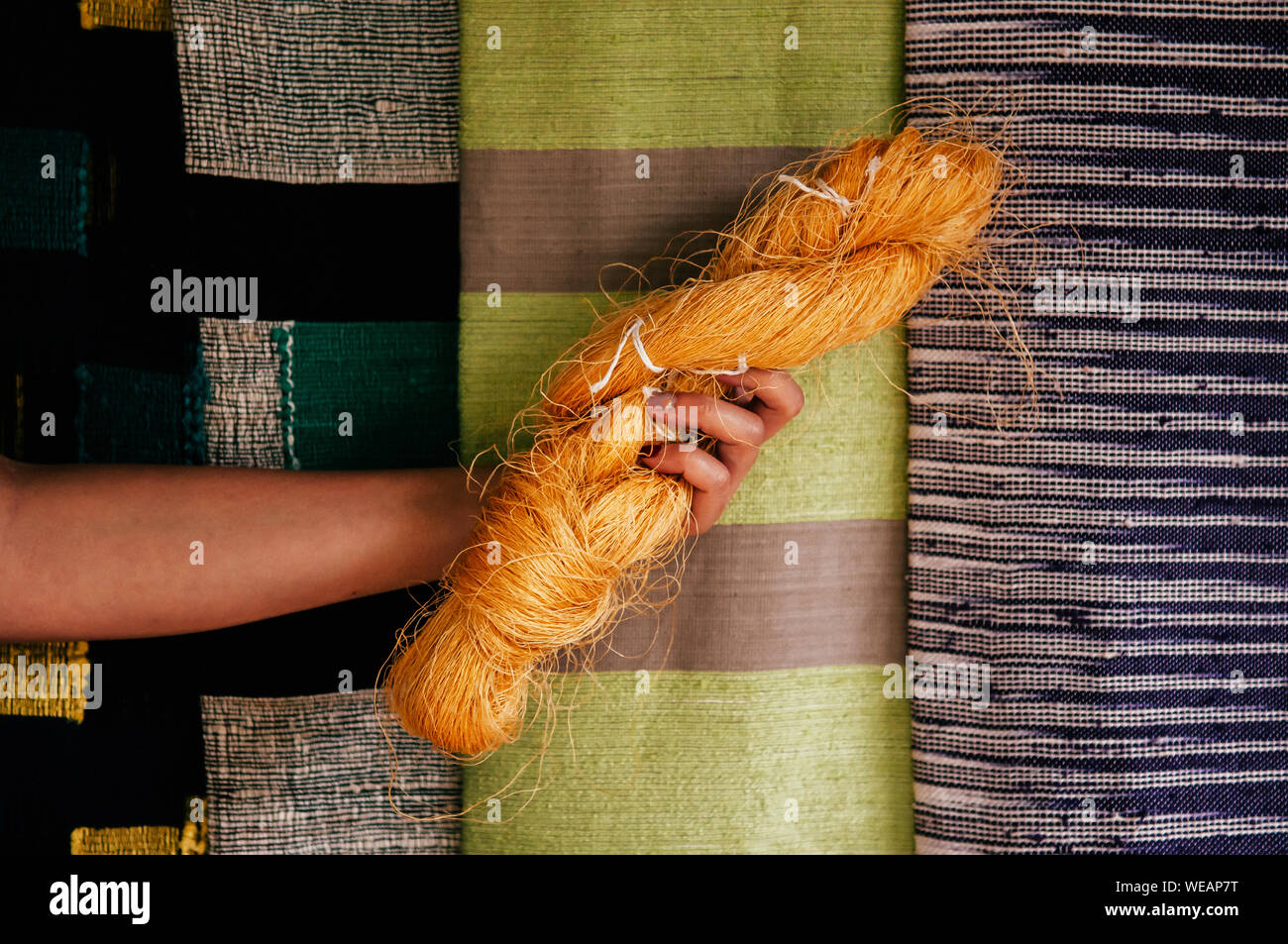 Hand holding natural yellow silk thread fiber. Raw material of ...