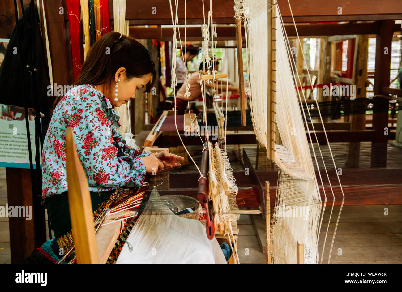 APR 4, 2018 Luang Prabang, Laos - Young woman working on Vintage Laos style wooden weaving loom ...