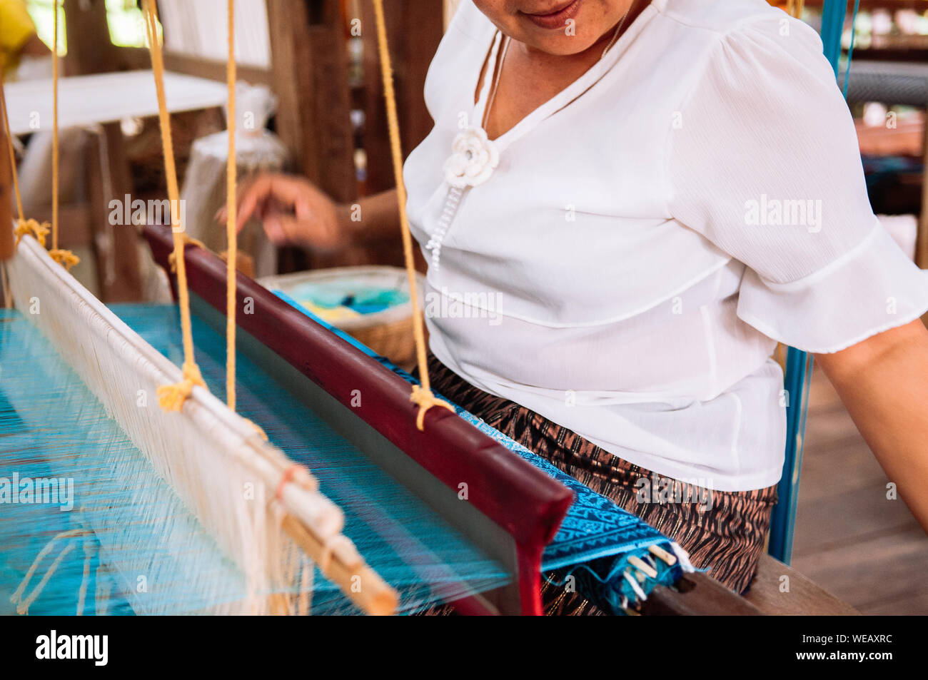 APR 4, 2018 Luang Prabang, Laos - Laotian woman working on Vintage Laos style wooden weaving ...