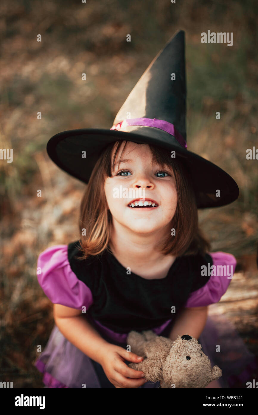 Smiling girl disguised as a witch in the woods during Halloween Stock ...