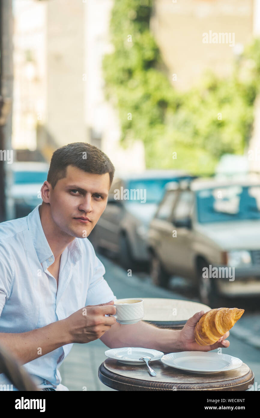 Man eat and drink coffee in street cafe. Macho enjoy cup of tea and ...