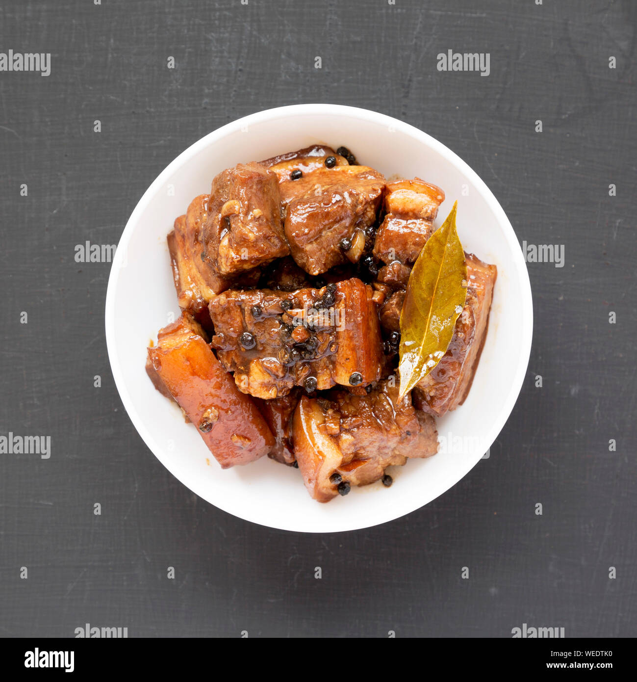 Homemade Filipino Adobo Pork in a white bowl on a black surface, top ...