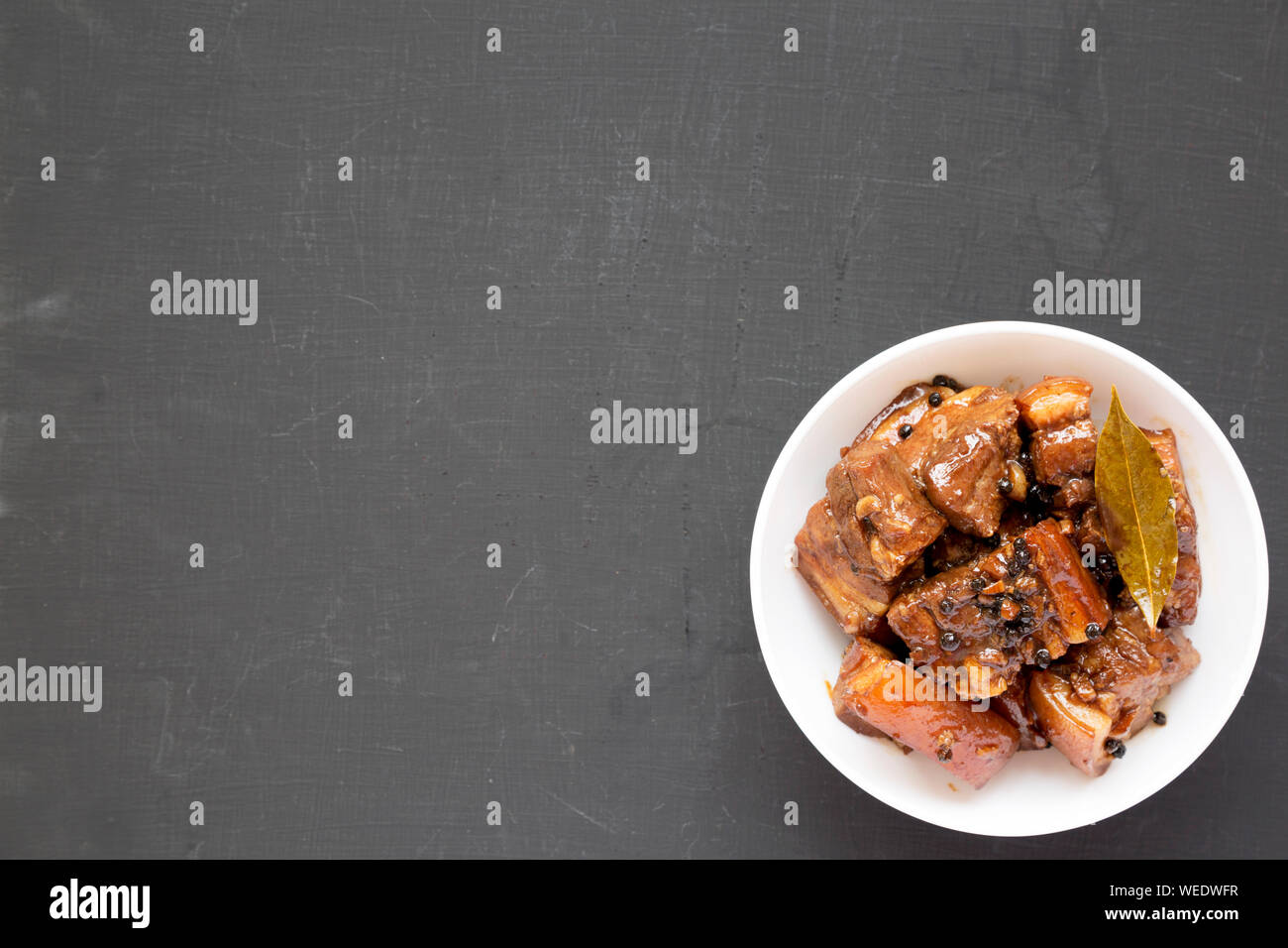 Homemade Filipino Adobo Pork in a white bowl on a black background, top ...