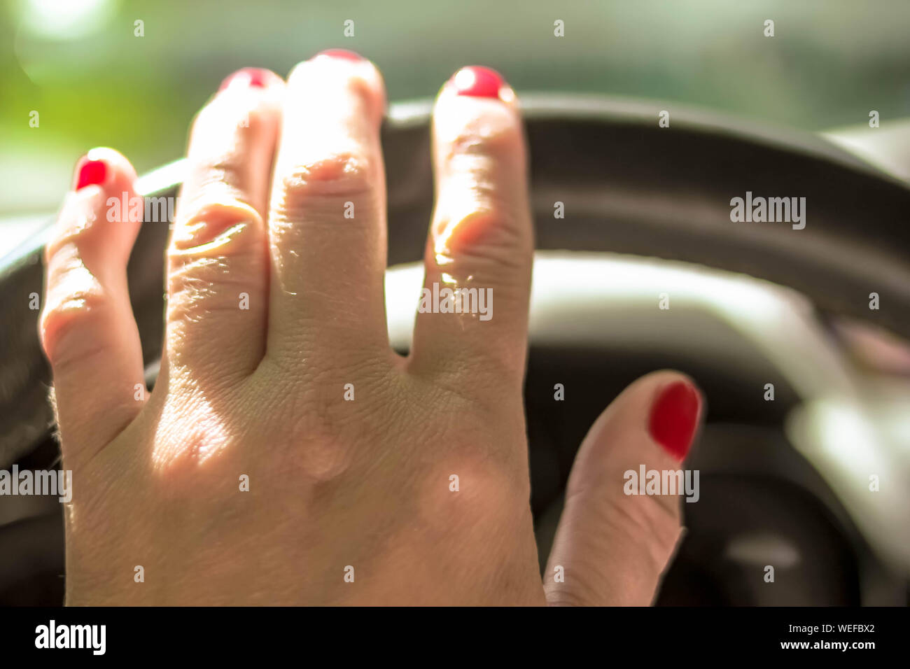 Woman driving a car with one hand holding the steering wheel with ...