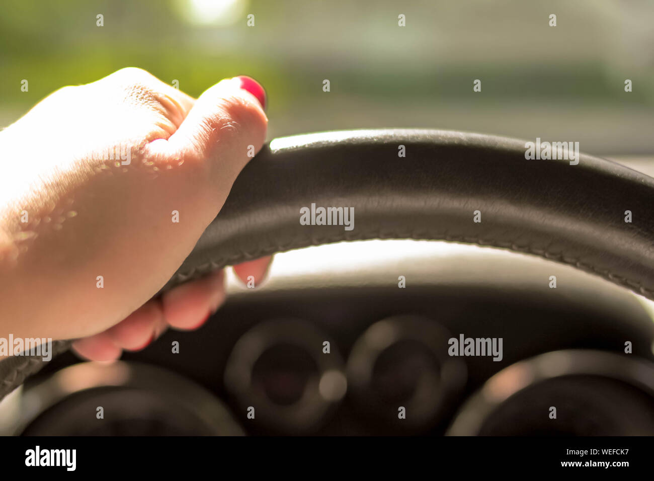 Woman driving a car with one hand holding the steering wheel with ...