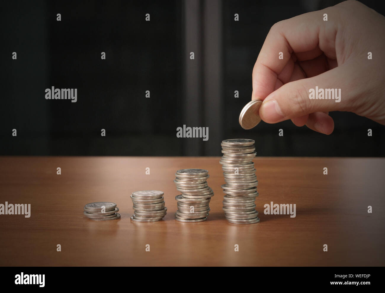 Hand putting stack of a coins Stock Photo - Alamy